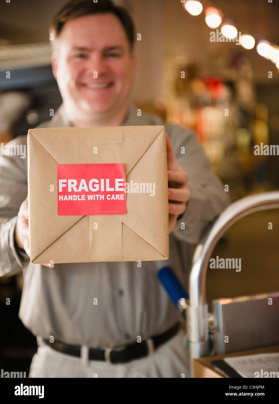 Delivery man holding box with fragile sign Stock Photo - Alamy