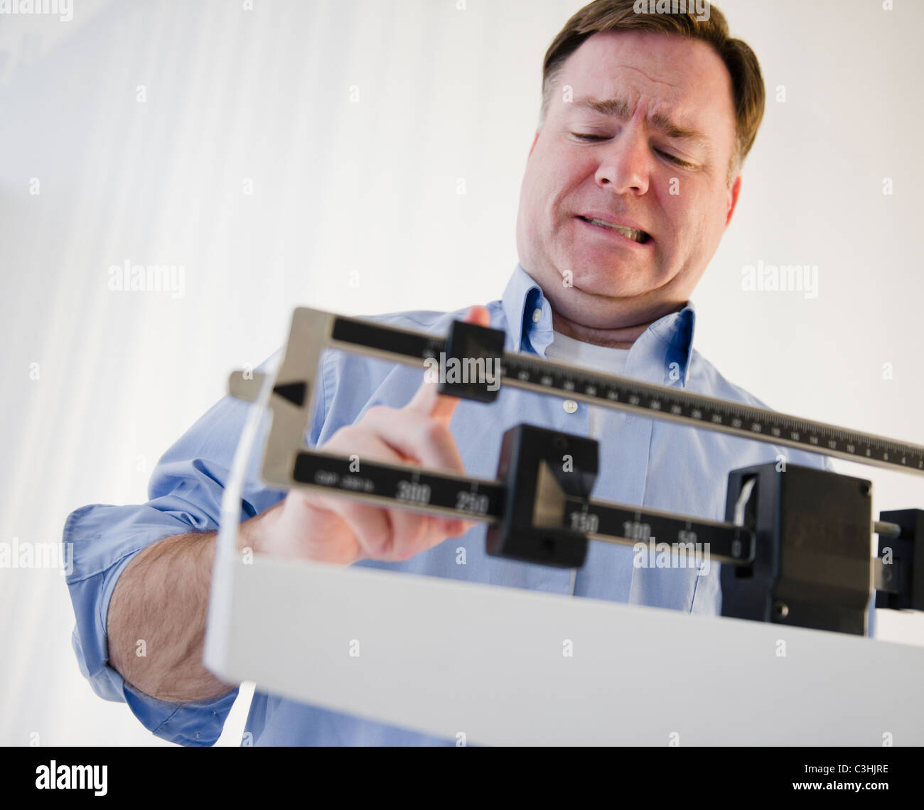 Man on weight scales Stock Photo - Alamy