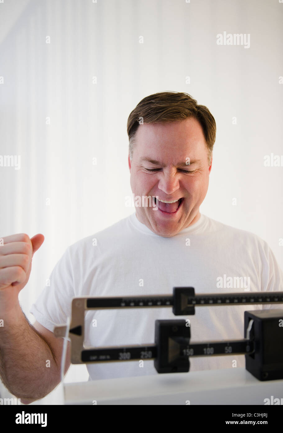 Man on weight scales laughing Stock Photo - Alamy