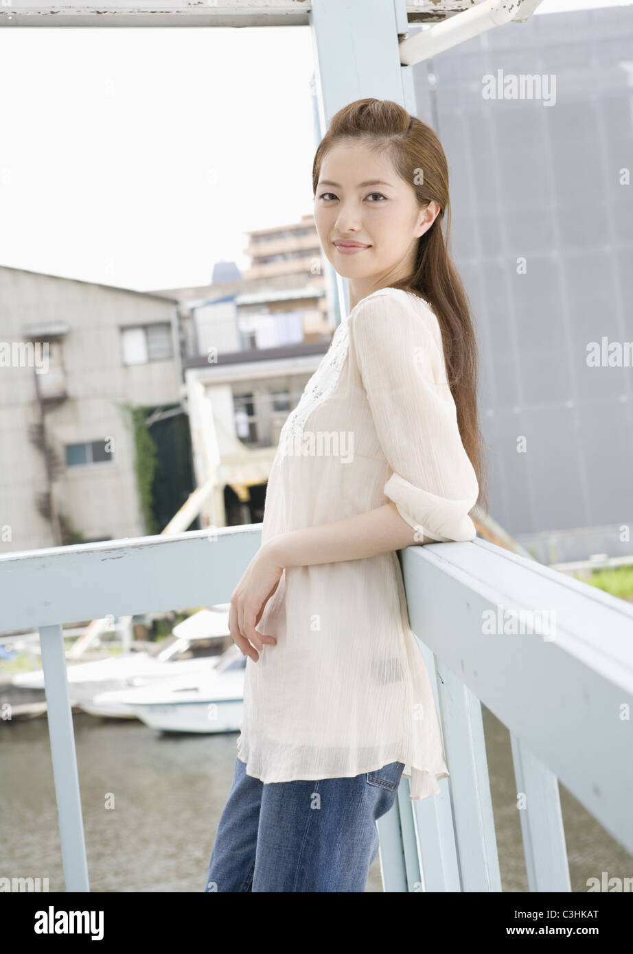 Young woman leaning on railing Stock Photo - Alamy