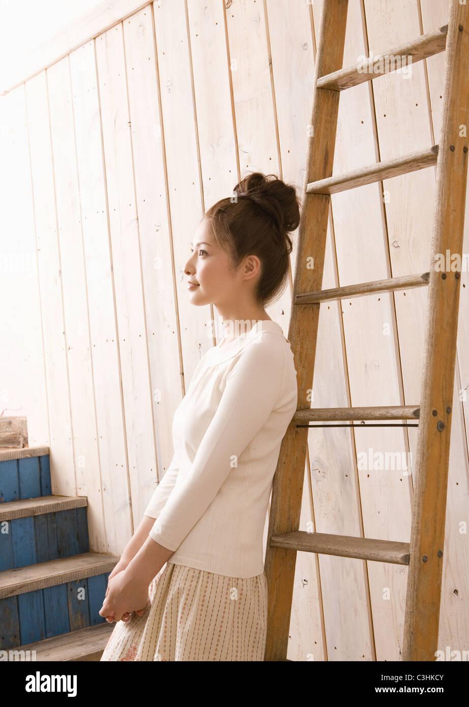 Young woman leaning on ladder Stock Photo - Alamy