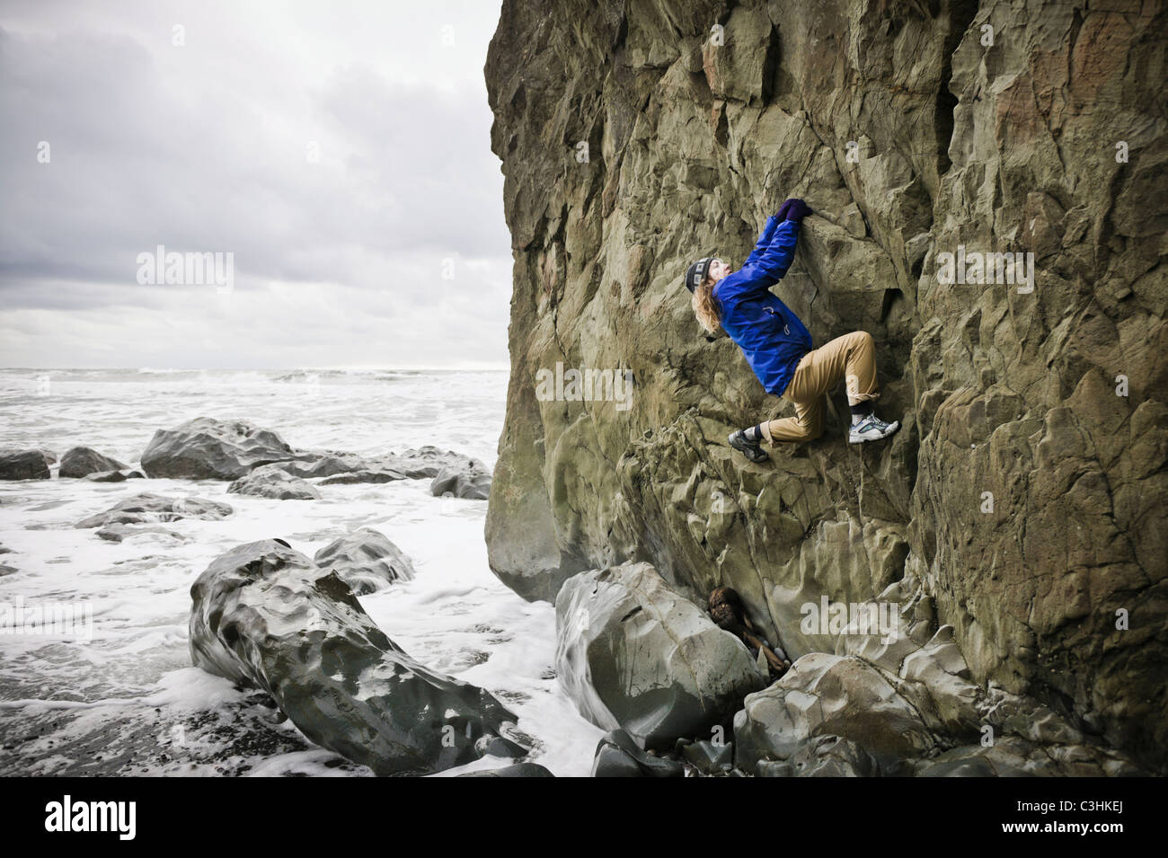 A woman bouldering on a sea stack on Rialto beach on the coast of ...