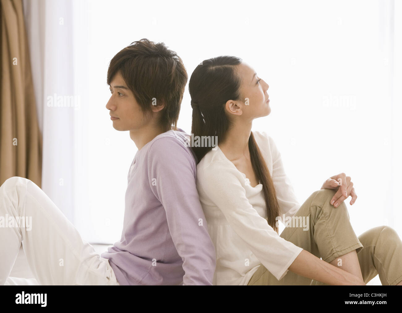 Couple sitting back to back Stock Photo - Alamy