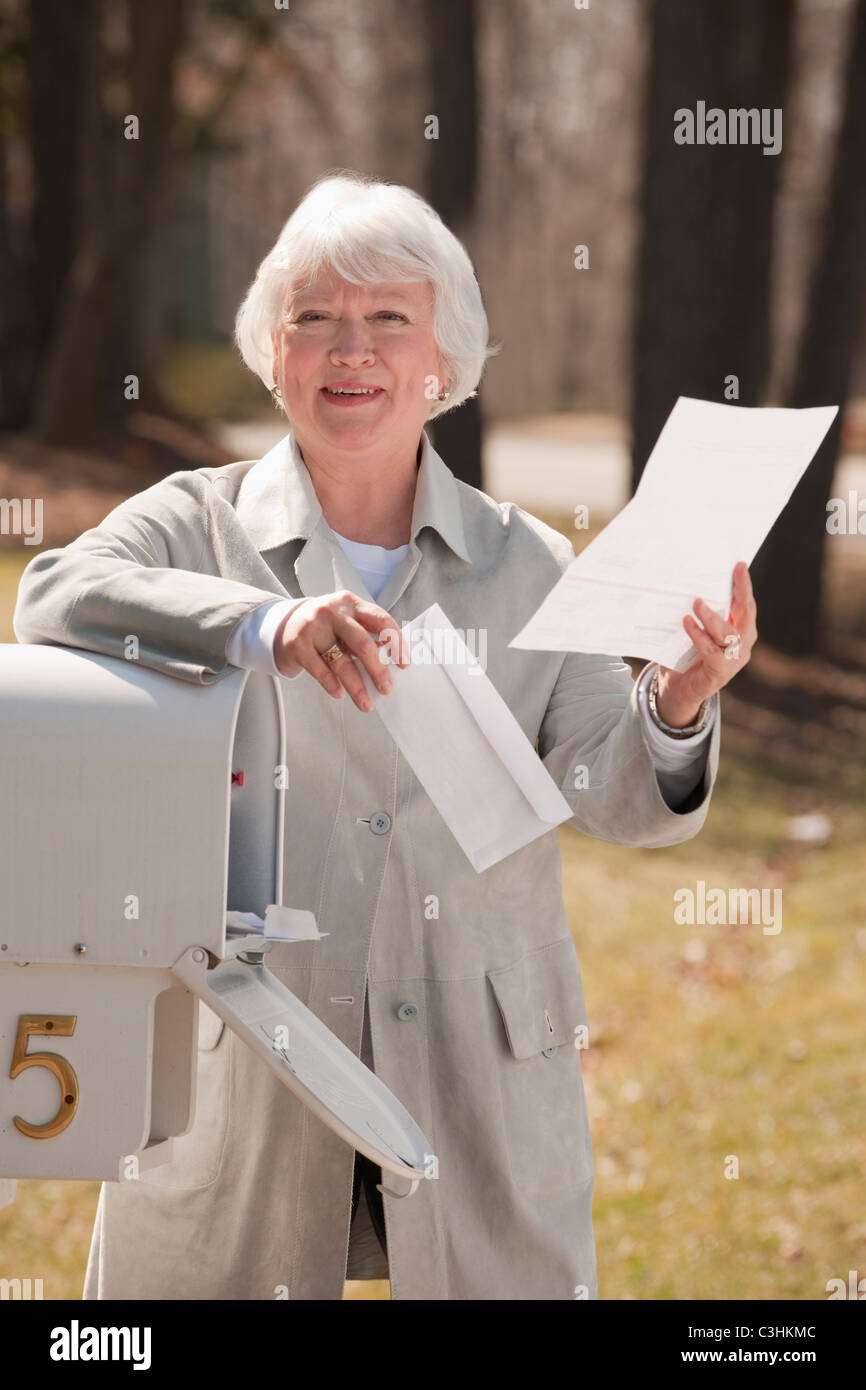Senior woman reading letters by mailbox Stock Photo - Alamy