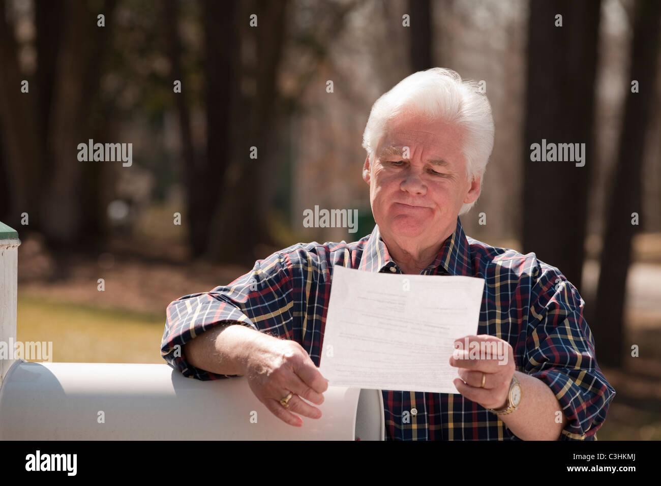 Senior man reading letter by mailbox Stock Photo - Alamy