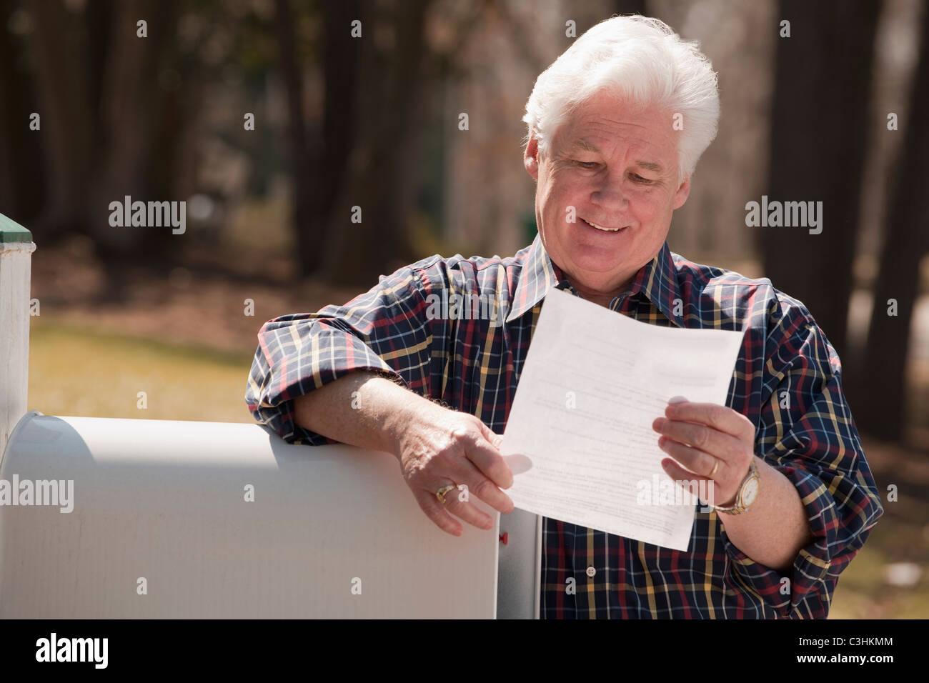 Senior man reading letter by mailbox Stock Photo - Alamy