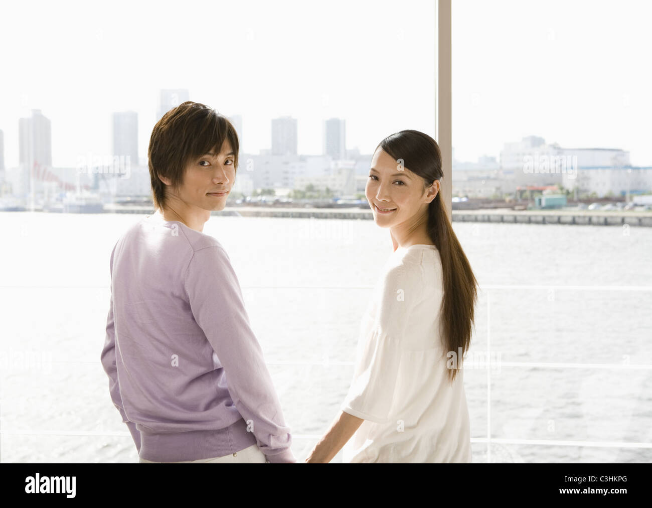 Couple standing by window Stock Photo - Alamy