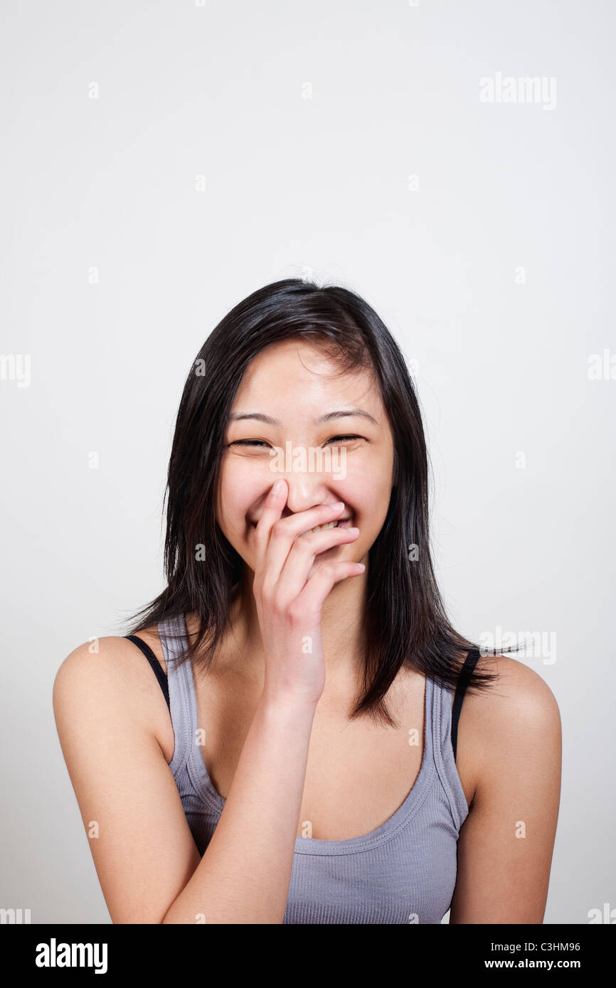 Young woman covering mouth when laughing Stock Photo - Alamy
