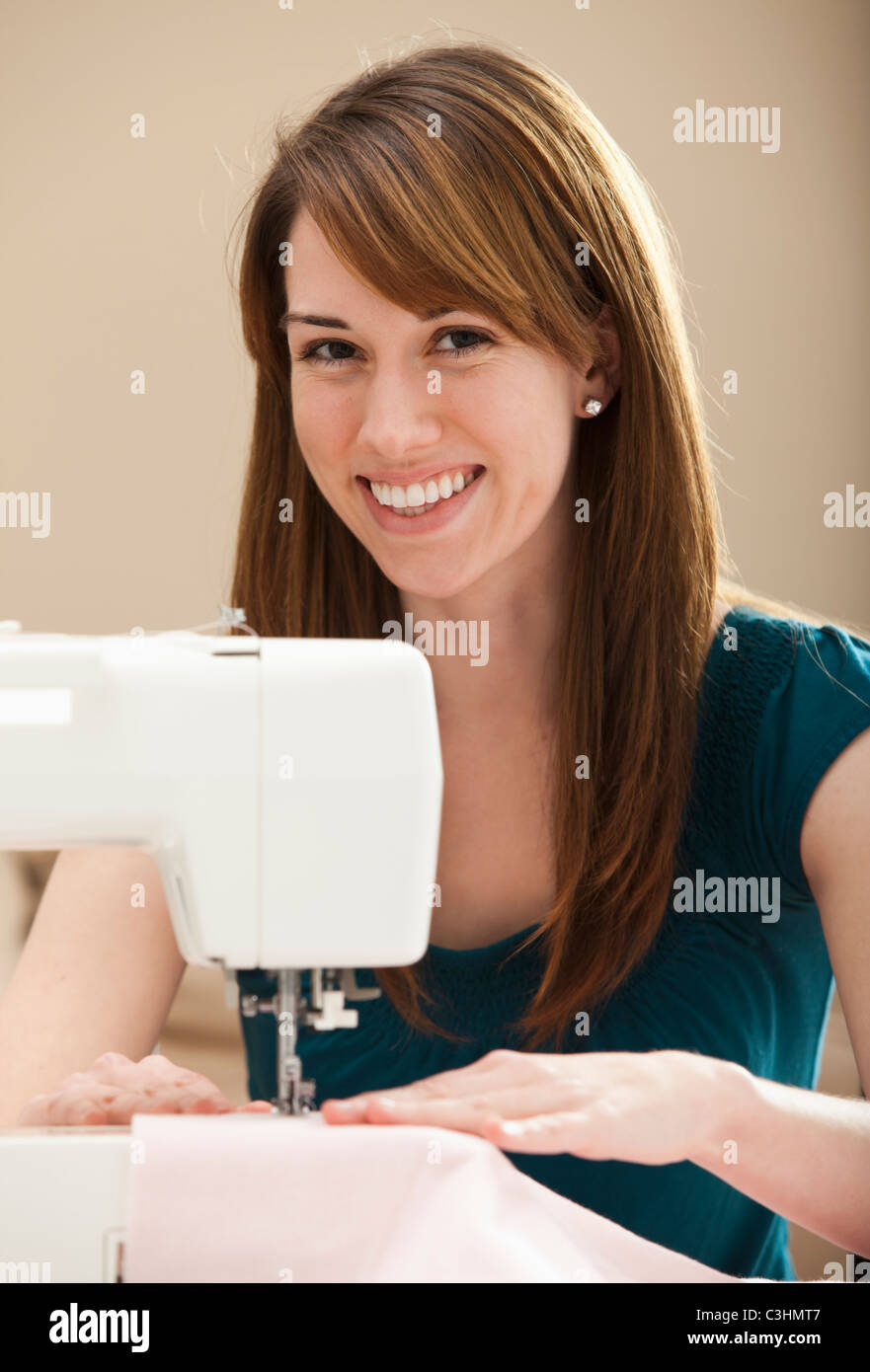 Portrait of smiling young woman using sewing machine Stock Photo - Alamy