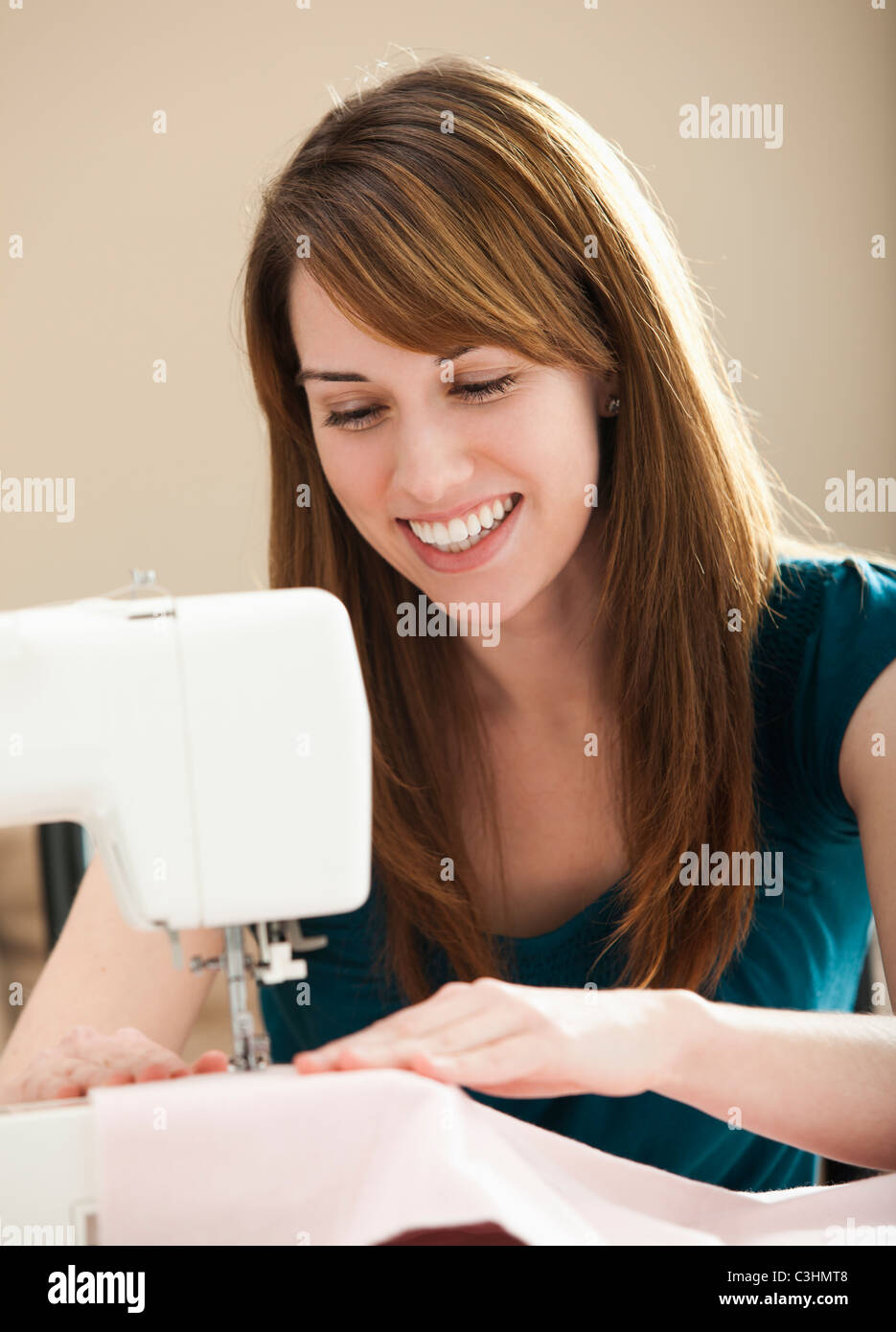 Smiling young woman using sewing machine Stock Photo - Alamy