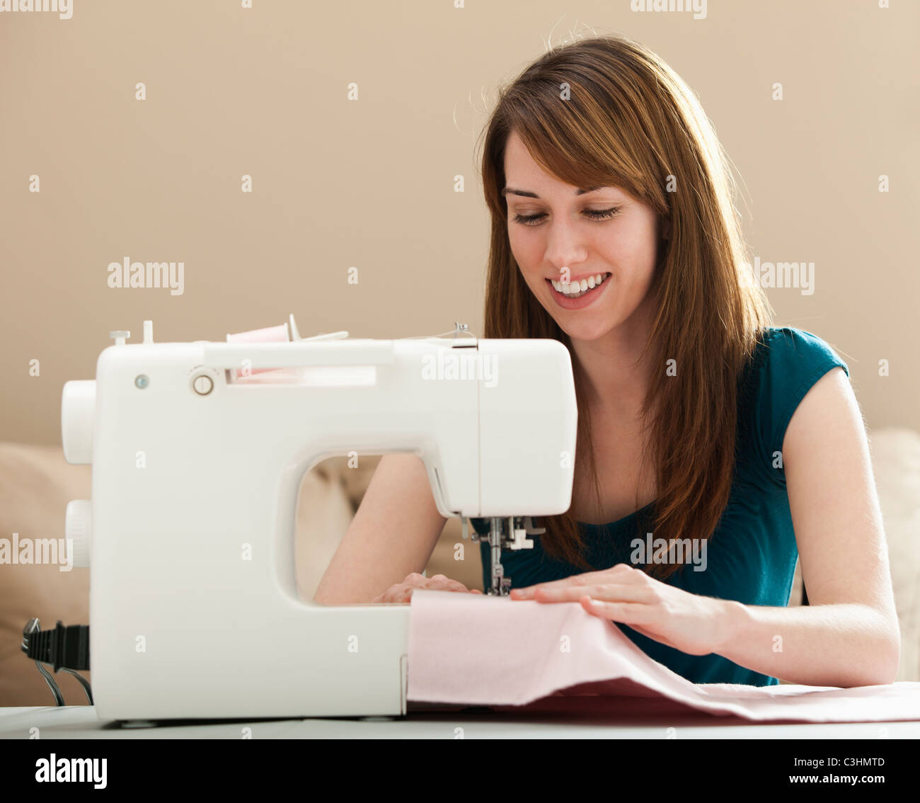 Smiling young woman using sewing machine Stock Photo - Alamy