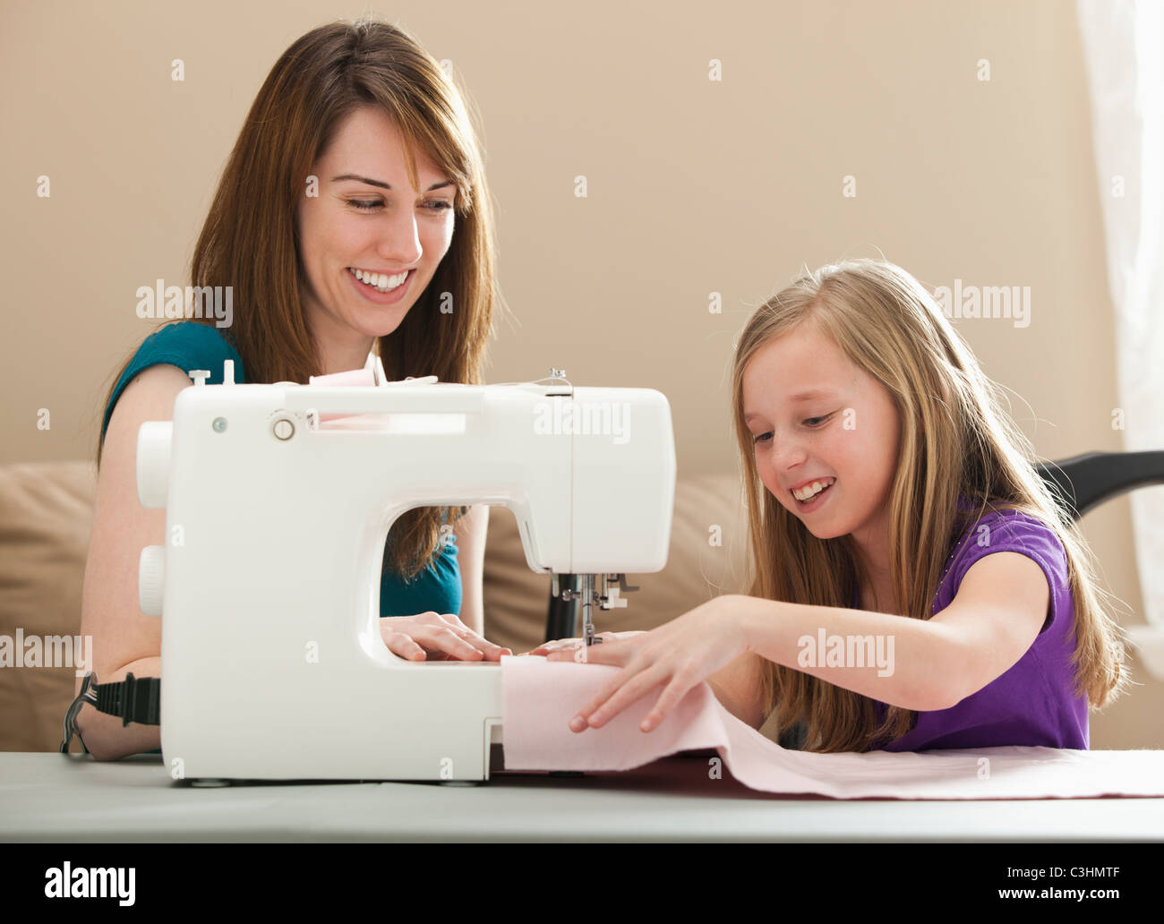 Girl (8-9) and young woman using sewing machine Stock Photo - Alamy