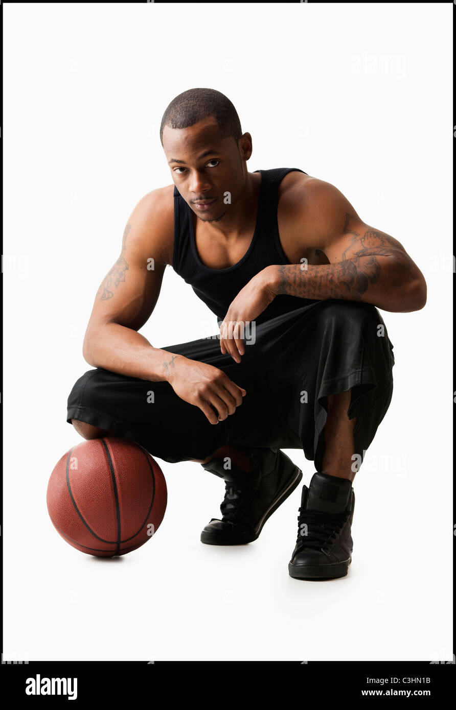 Studio shot of man with basketball crouching Stock Photo - Alamy