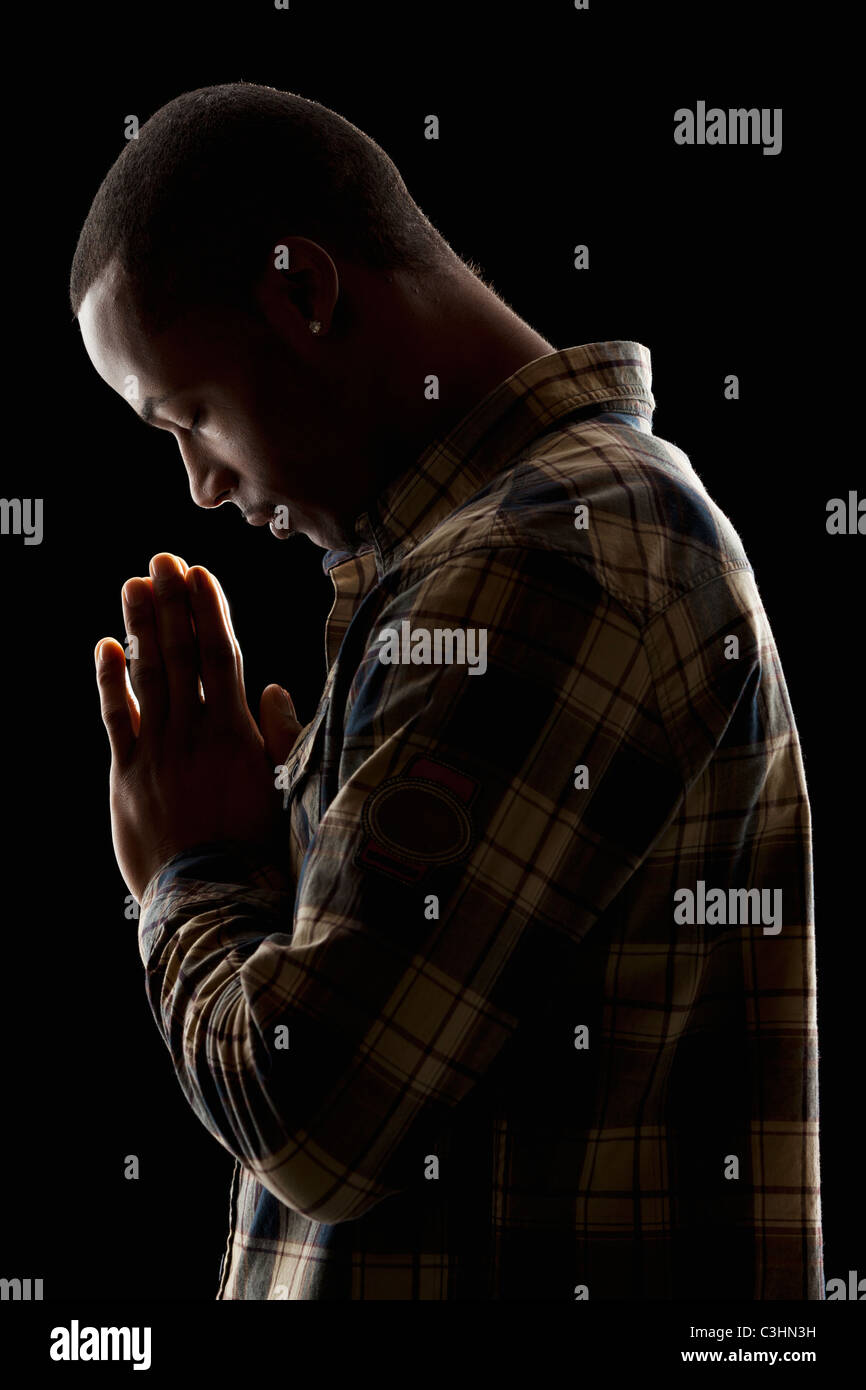 Studio shot of young man praying Stock Photo - Alamy