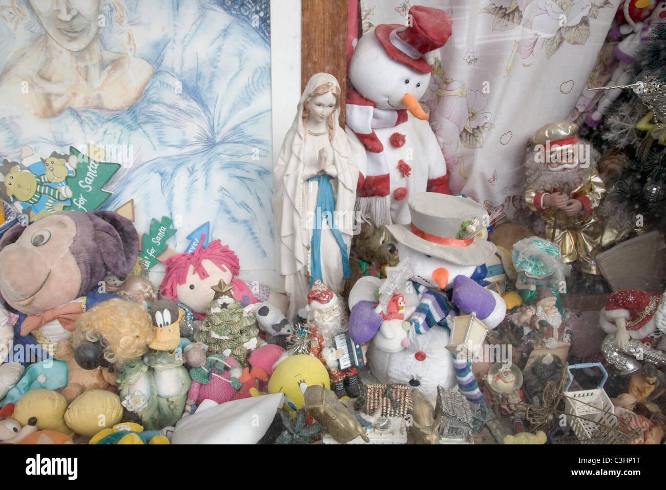 Window display of dolls a snowman and a small statue of the Virgin ...