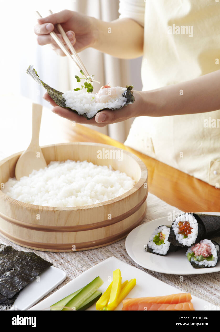 Closeup of hands making hand-rolled sushi Stock Photo - Alamy