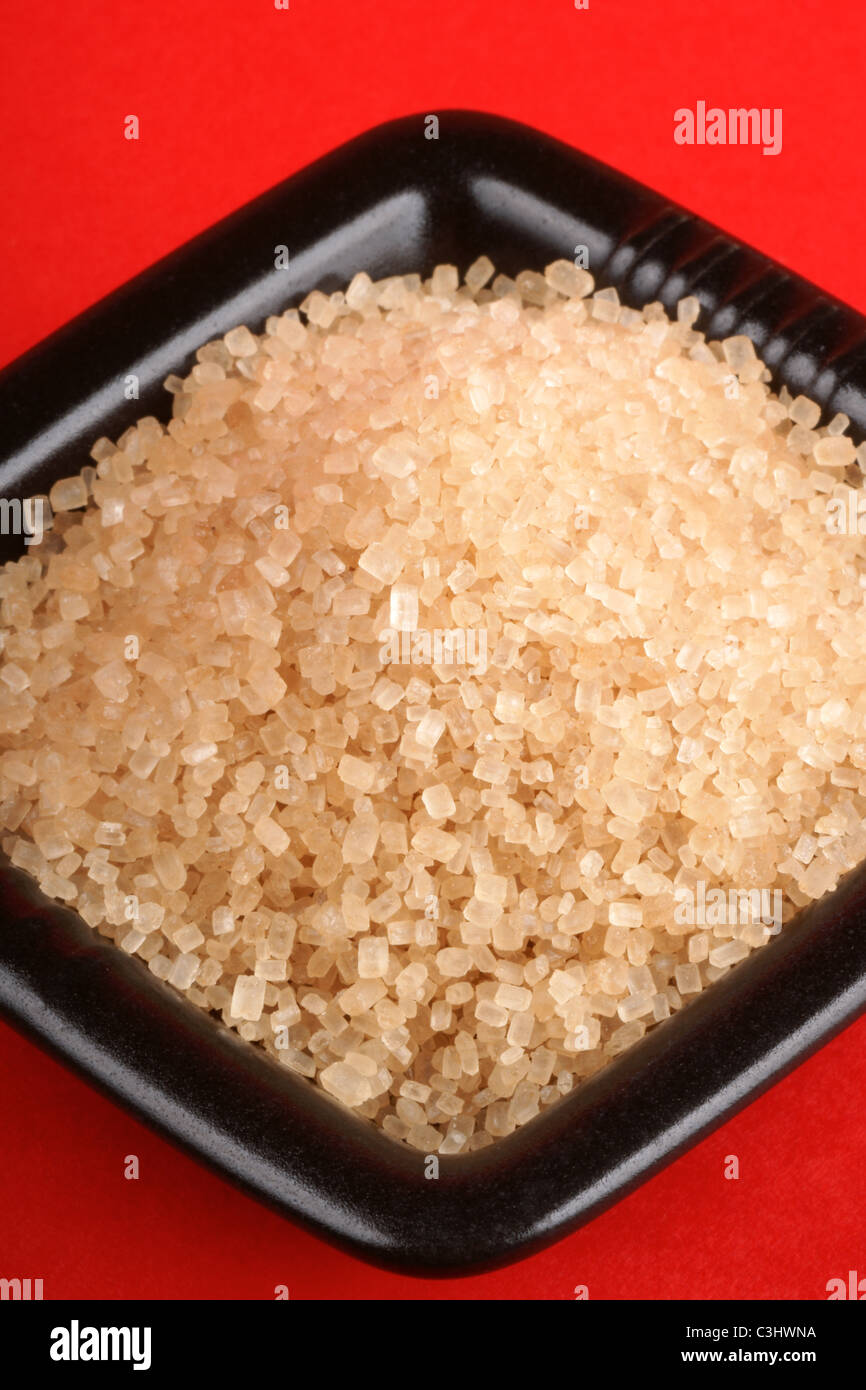 Brown sugar in a black bowl over a red background Stock Photo - Alamy