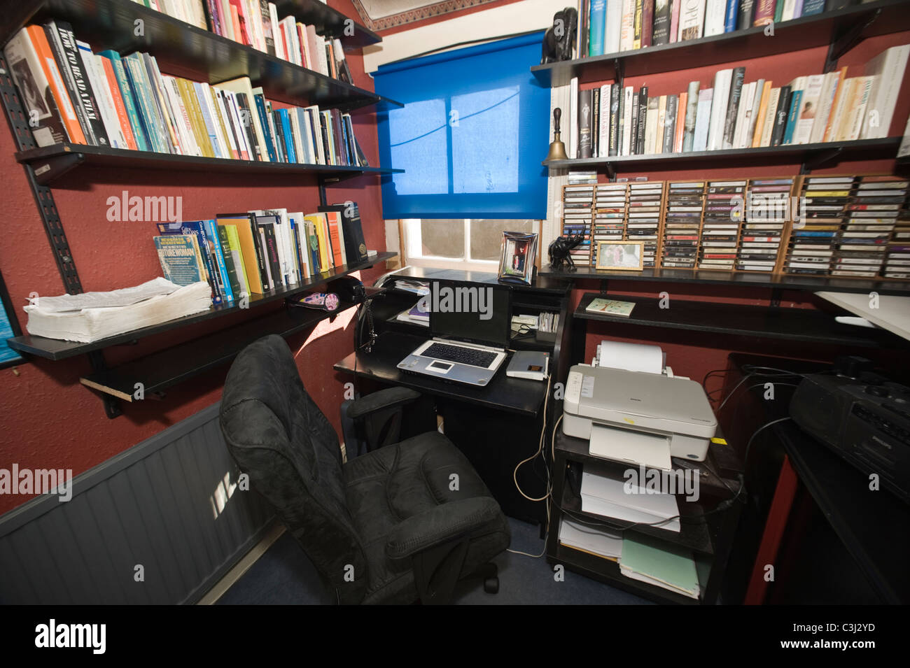 Small writer's study with desk office chair laptop computer bookshelves ...