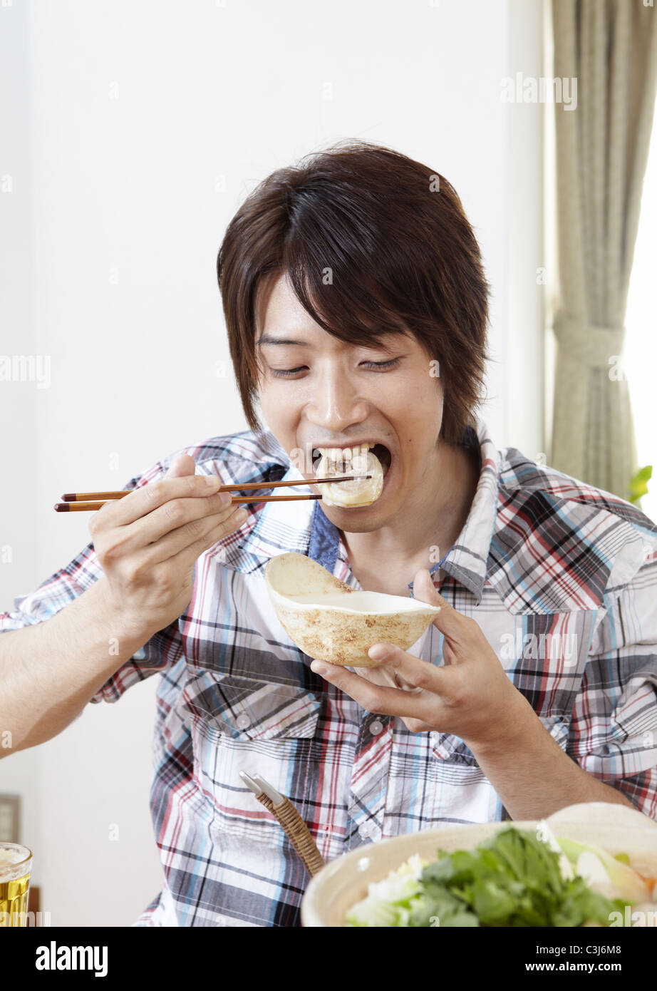 Young man eating Japanese hot pot Stock Photo - Alamy