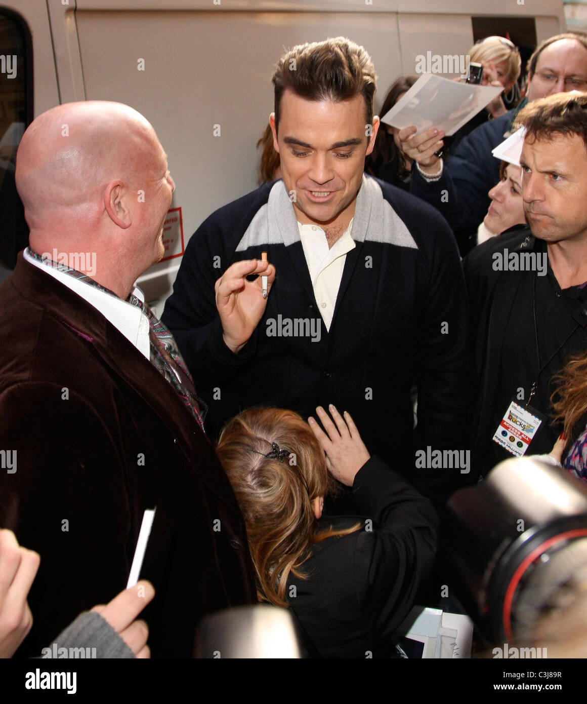 Robbie Williams signs autographs for fans while smoking a cigarette ...