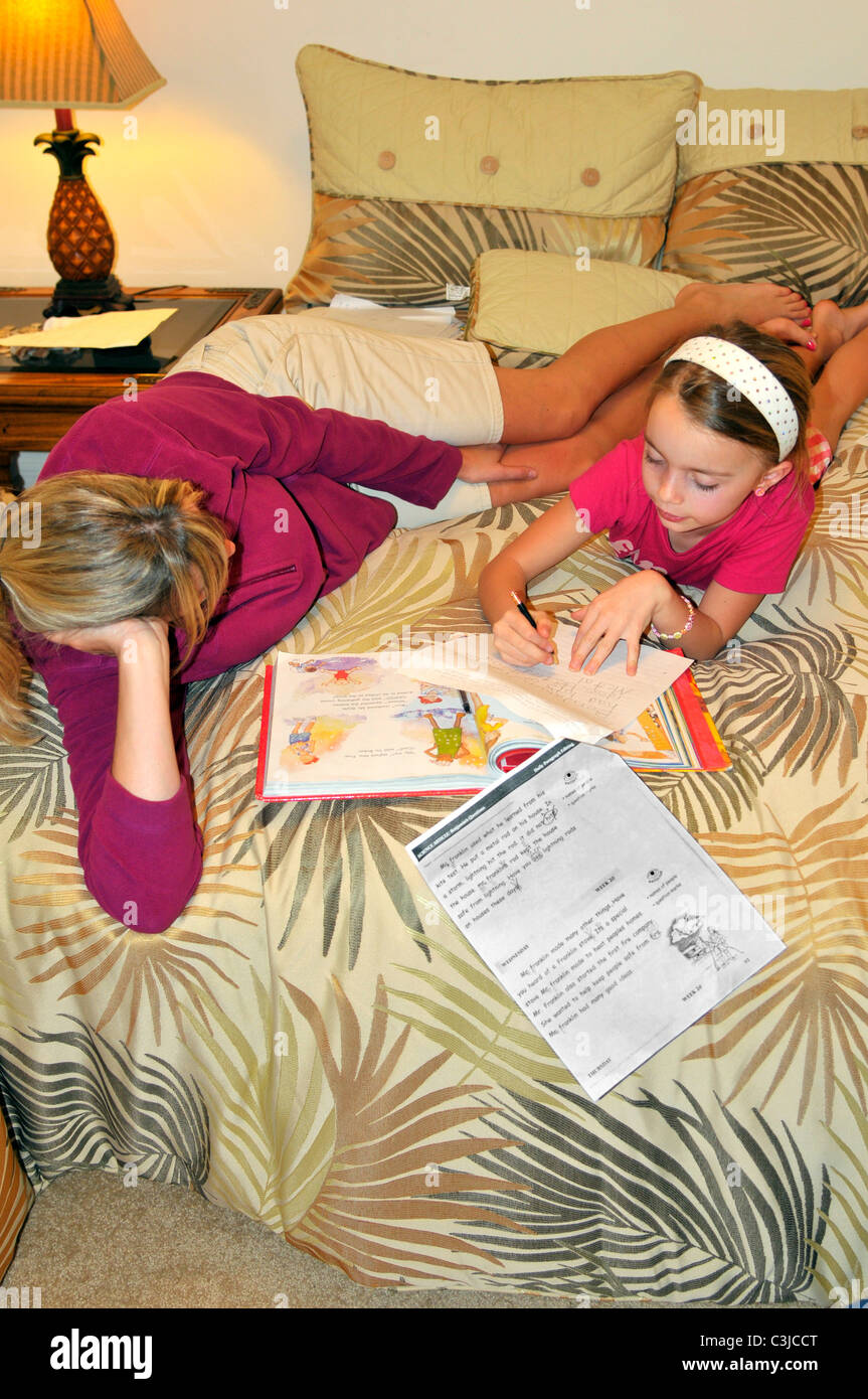Mother helping her 2nd grade daughter do homework on the bed Stock ...