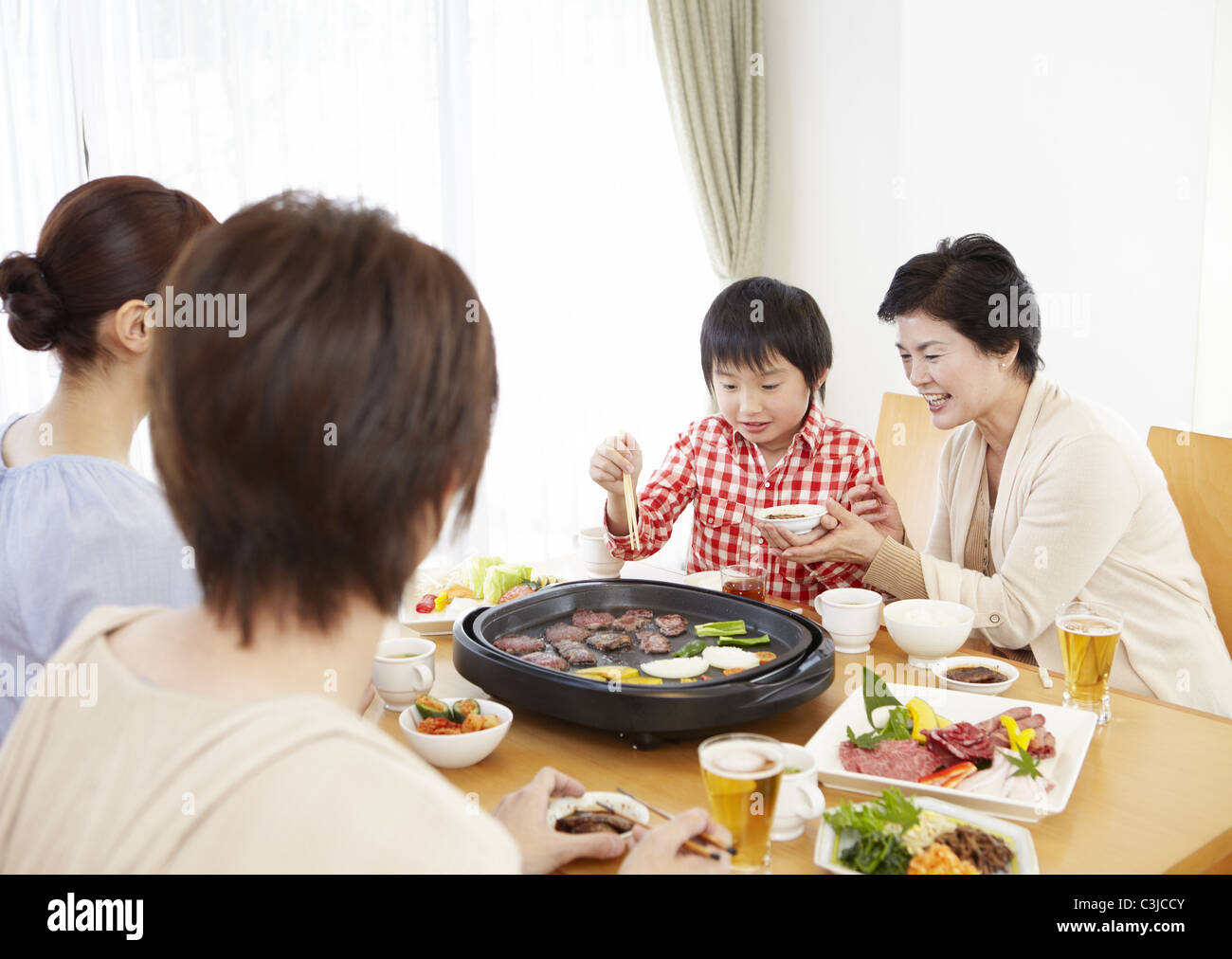 Three-generation family eating Japanese barbeque Stock Photo - Alamy