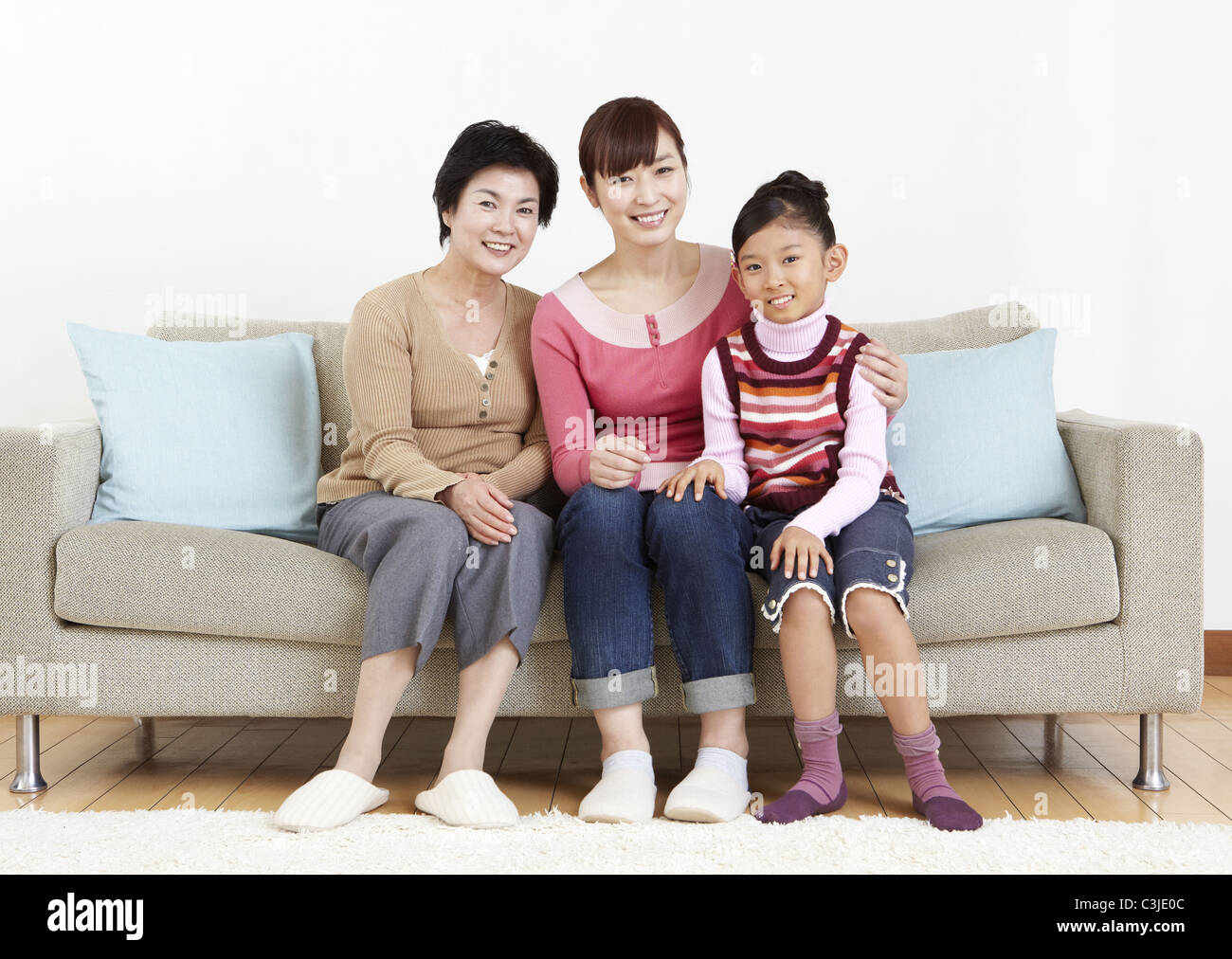 Three-generation family sitting on sofa Stock Photo - Alamy