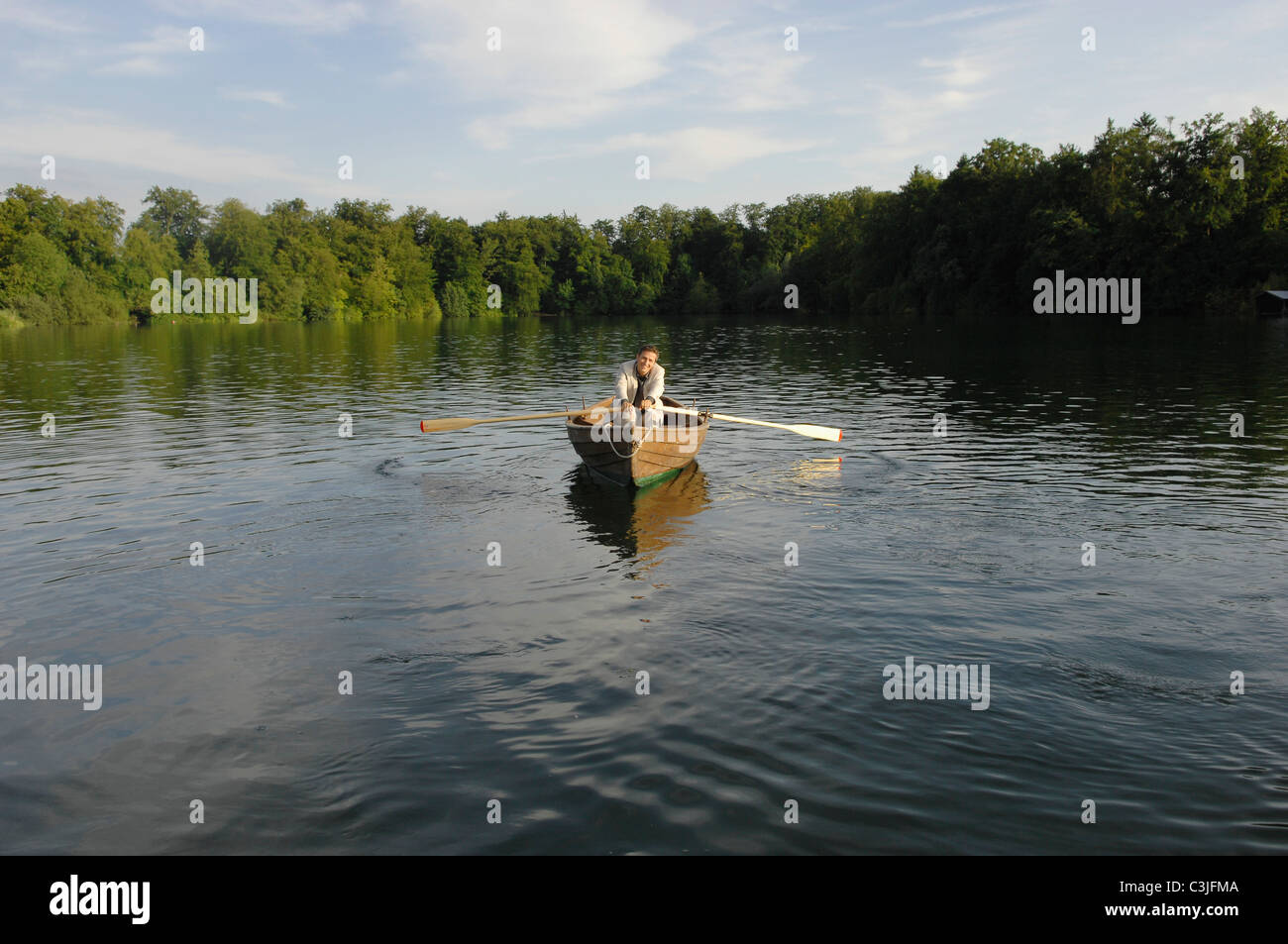 Germany, Bavaria, Wesslinger See, Business man rowing boat in lake ...