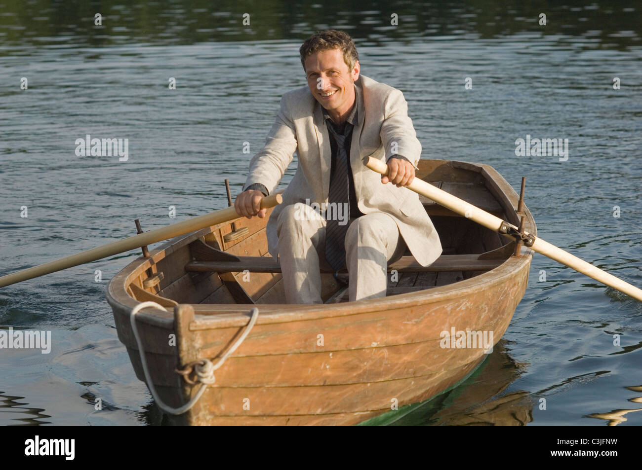Germany, Bavaria, Wesslinger See, Business man rowing boat in lake ...