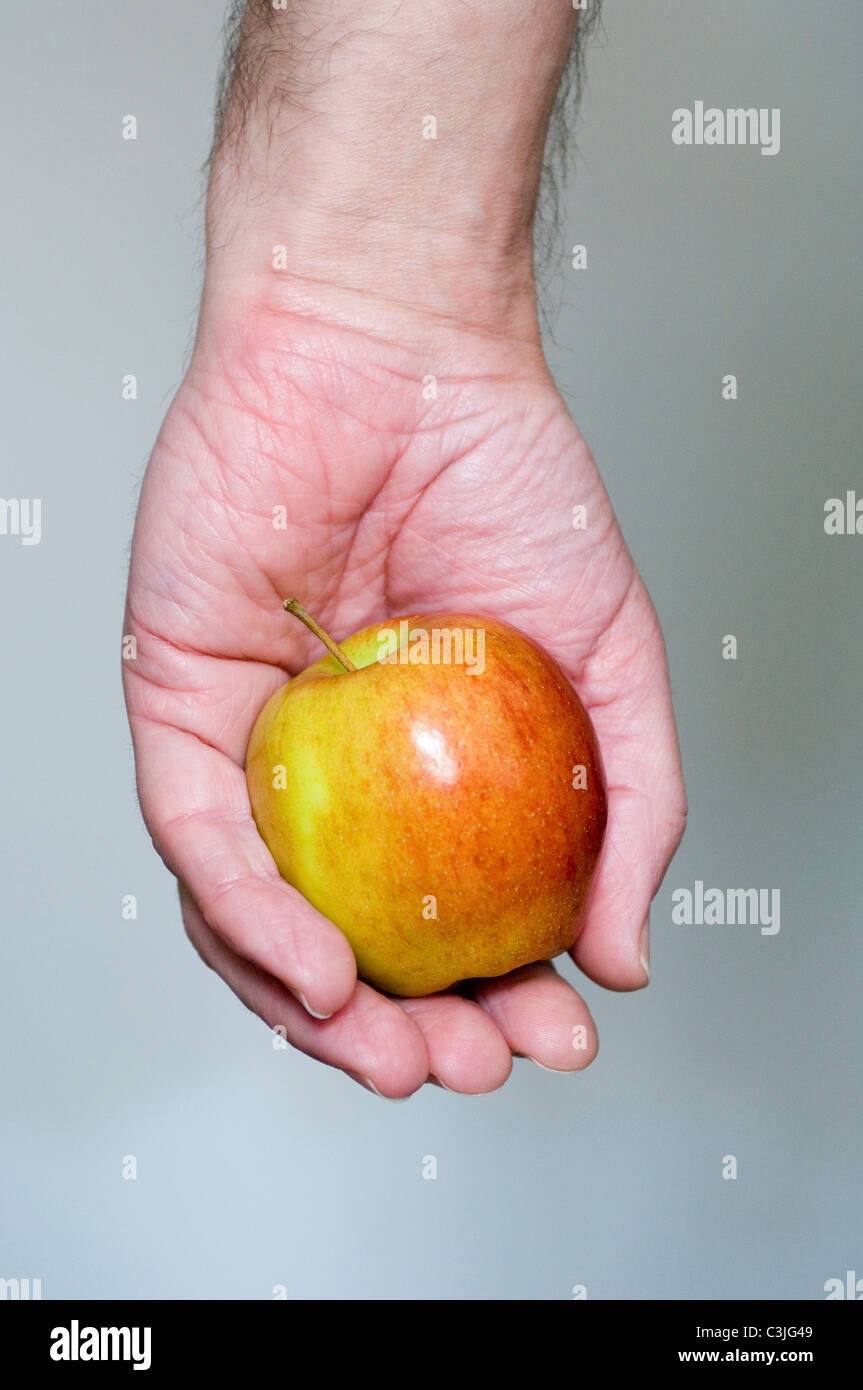 Mans hand holding an apple plain background Stock Photo - Alamy