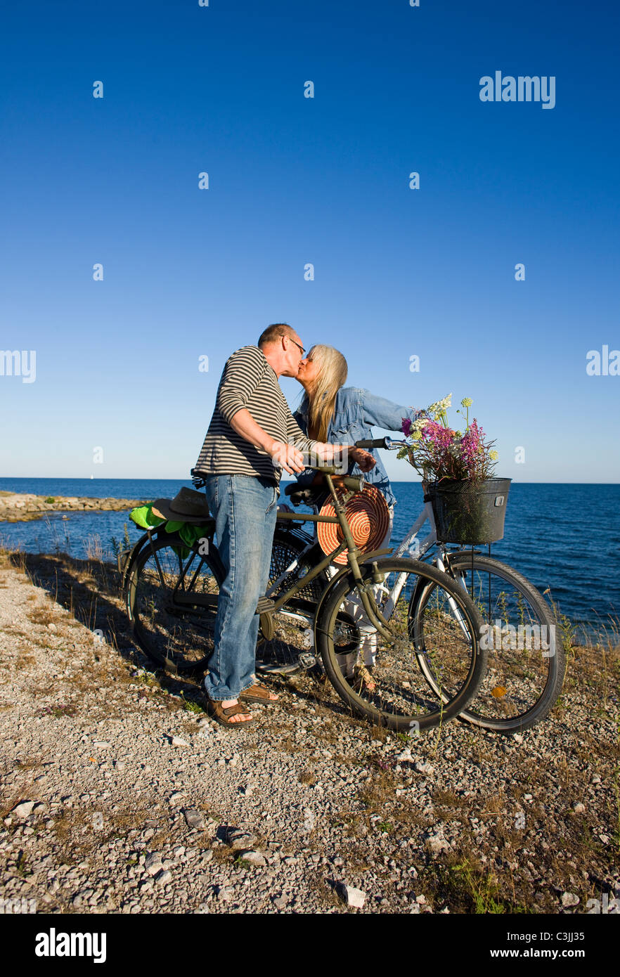 Mature couple riding bicycle on beach and kissing Stock Photo - Alamy