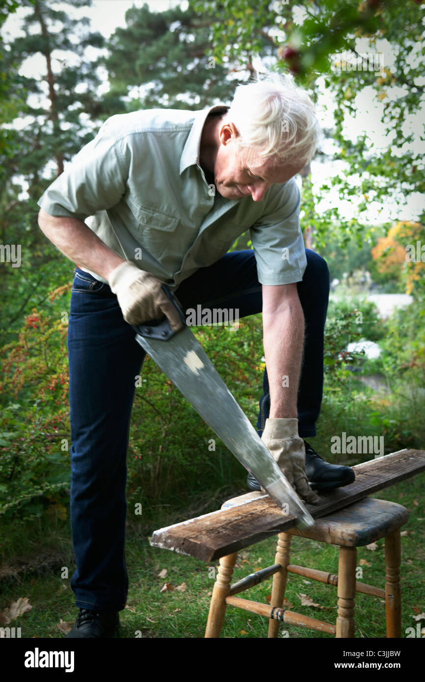 Senior man sawing plank Stock Photo - Alamy