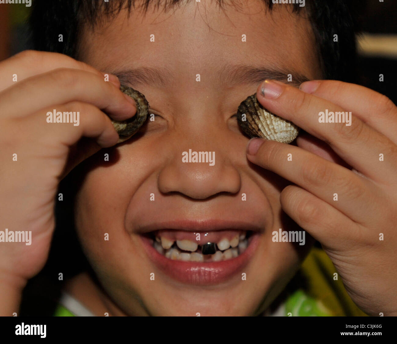 little boy with silver tooth covering his eyes with cockles , funny ...