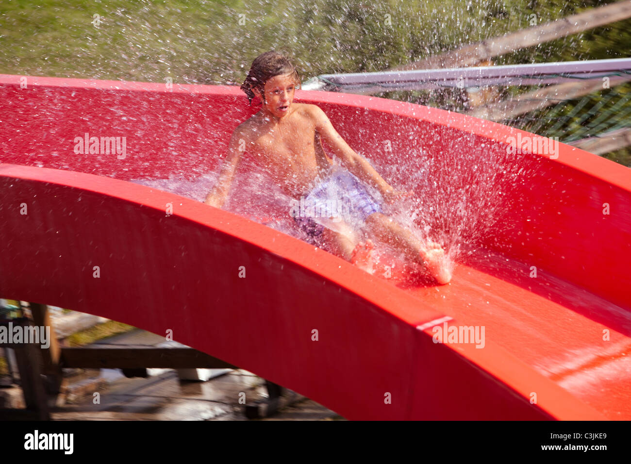 Boy sliding down water slide in water park Stock Photo - Alamy