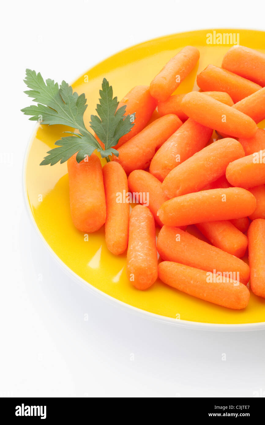 Baby carrot in plate on white background Stock Photo - Alamy