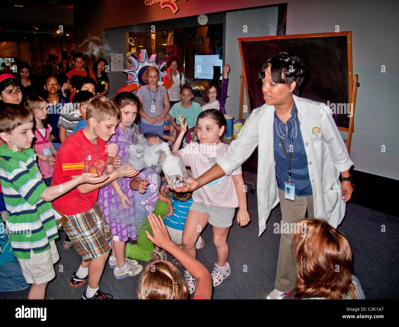 Children watch a science demonstration by an African American woman at ...