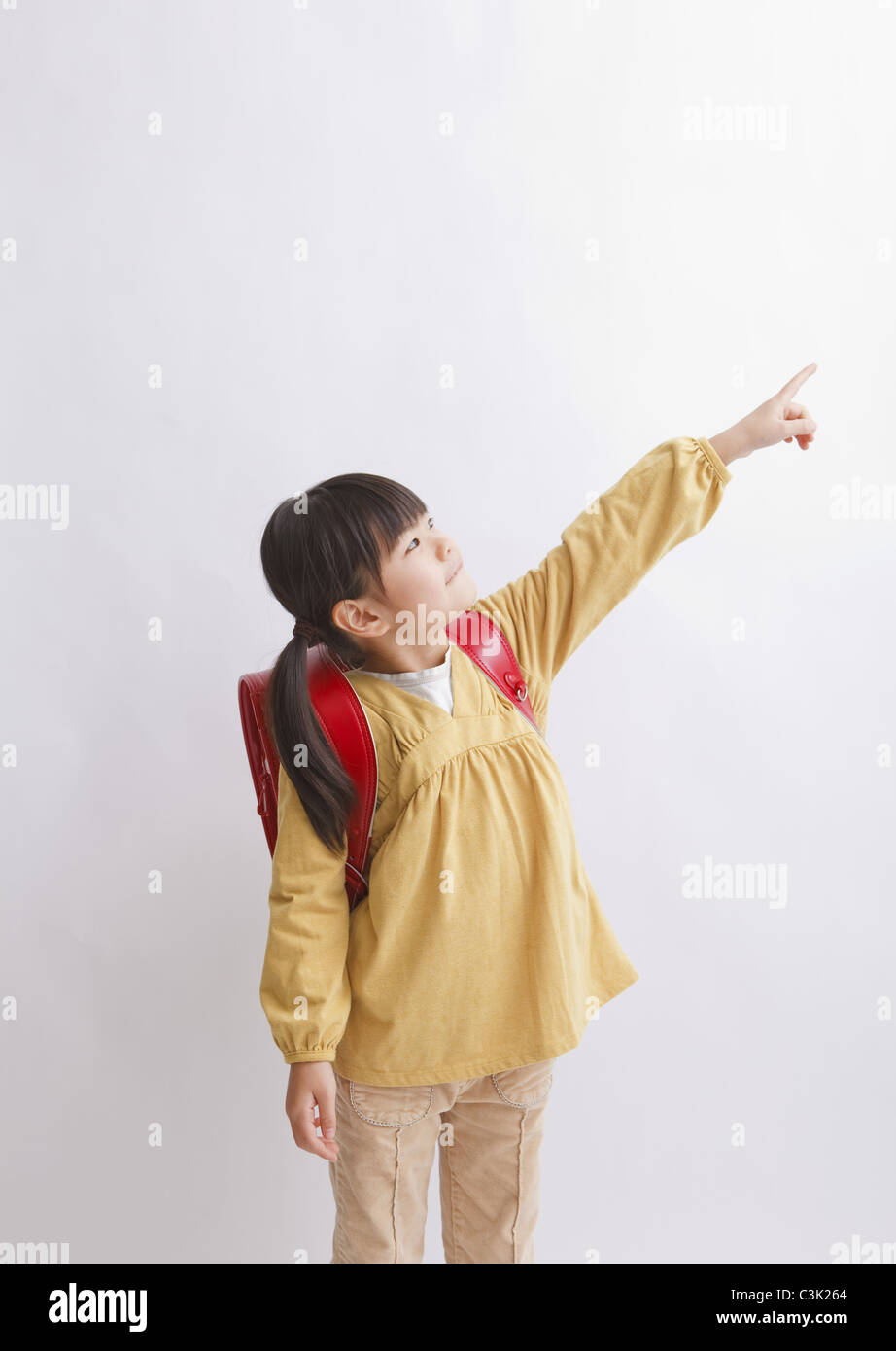 Girl with school bag pointing Stock Photo - Alamy