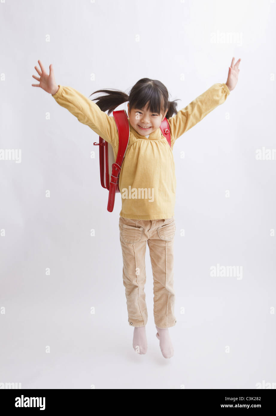 Jumping girl with school bag Stock Photo - Alamy
