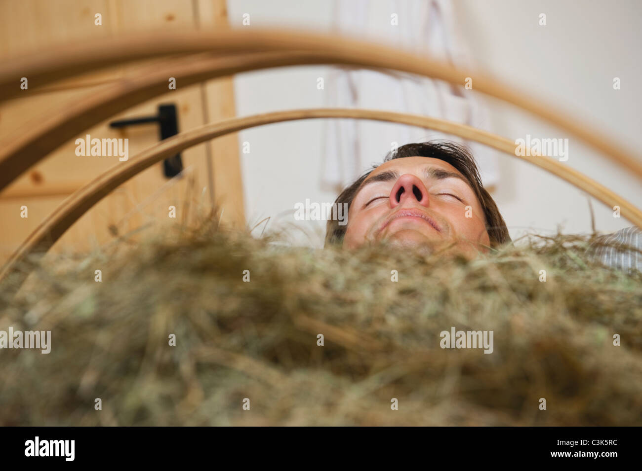 Italy, South Tyrol, Man having hay bath in hotel urthaler Stock Photo ...
