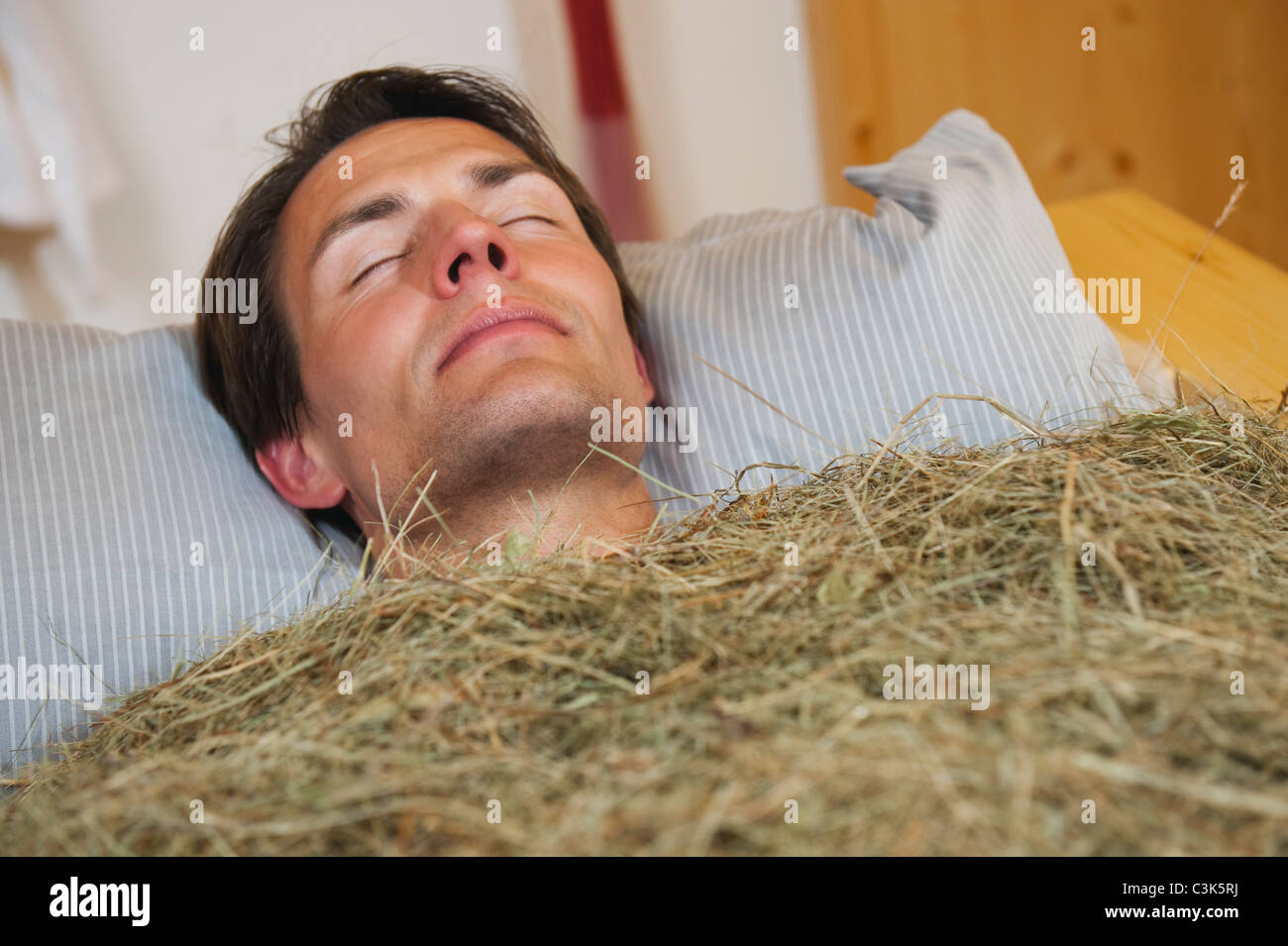 Italy, South Tyrol, Man having hay bath in hotel urthaler Stock Photo ...