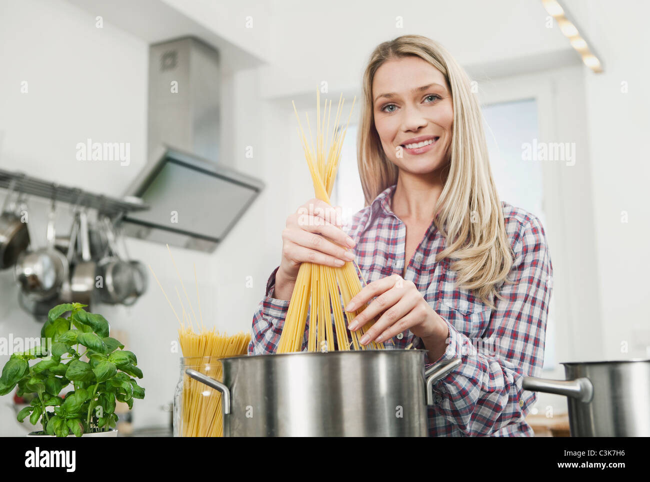 Germany, Cologne, Woman cooking spaghetti, portrait, smiling Stock ...