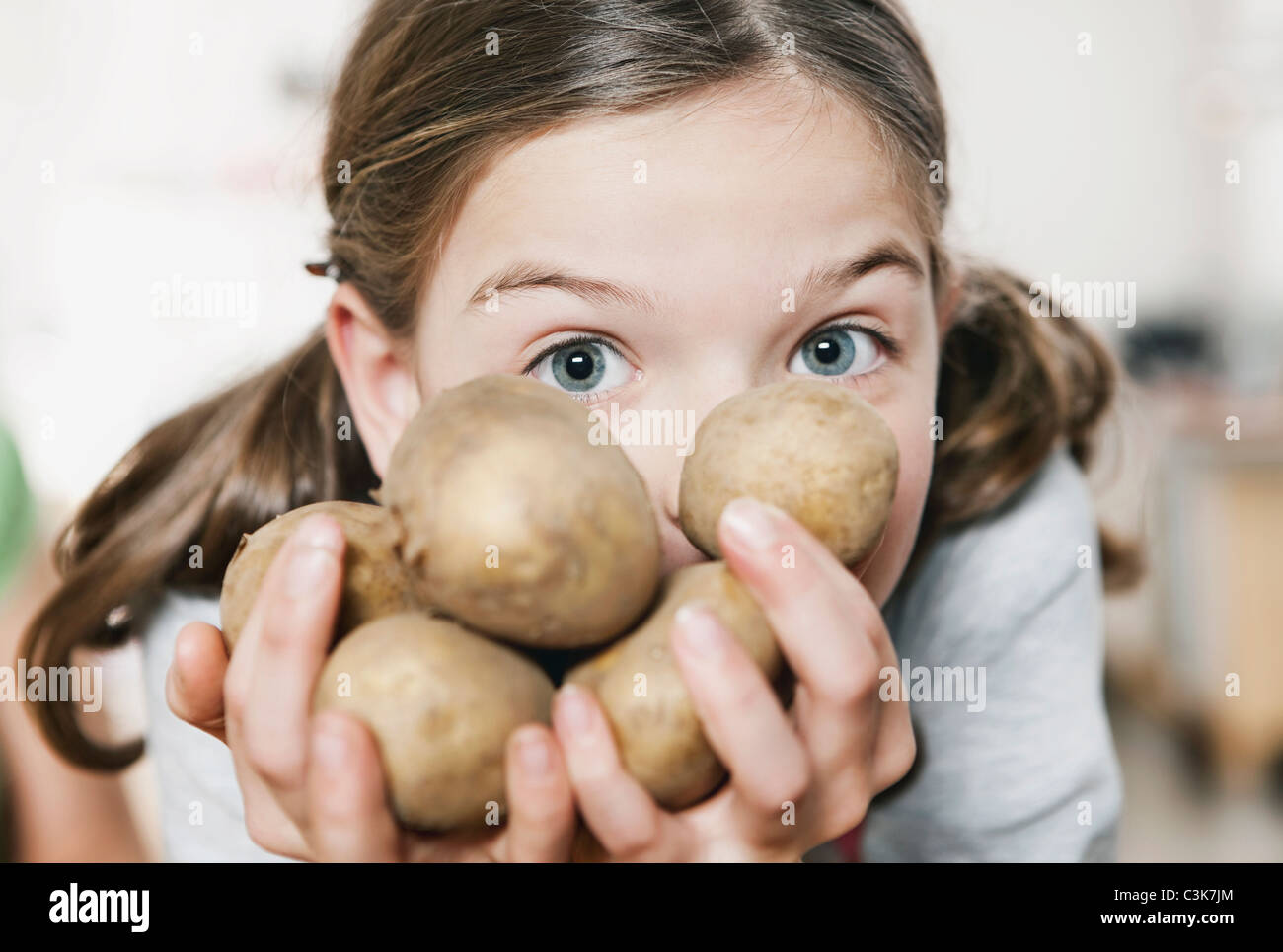 Germany, Cologne, Girl holding potatoes, portrait Stock Photo - Alamy