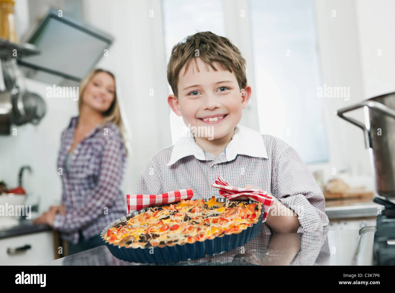 Germany, Cologne, Boy holding pizza with mother in background Stock ...