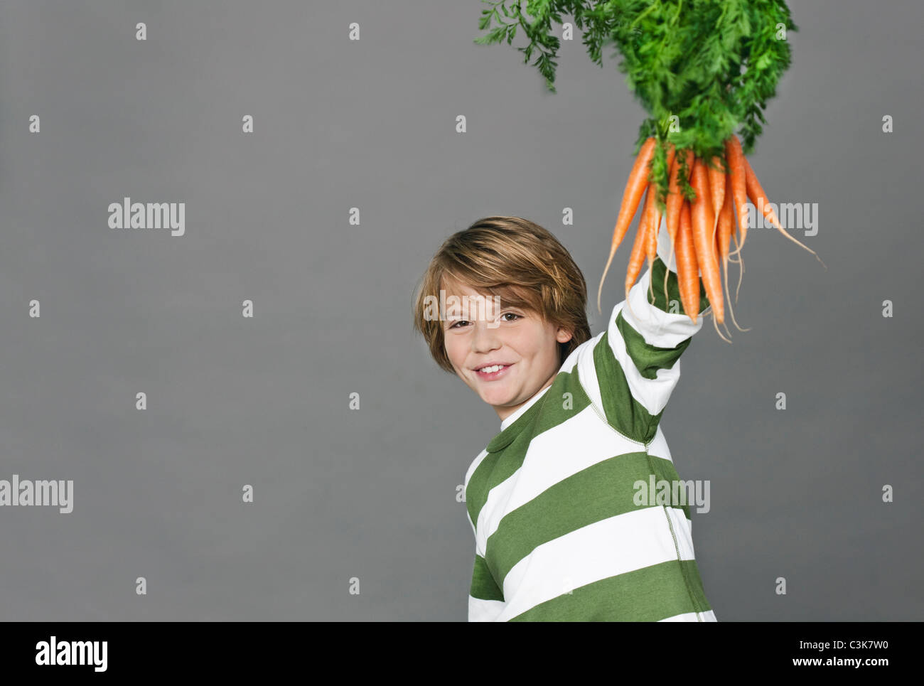 Boy holding a bunch of carrots, portrait Stock Photo - Alamy