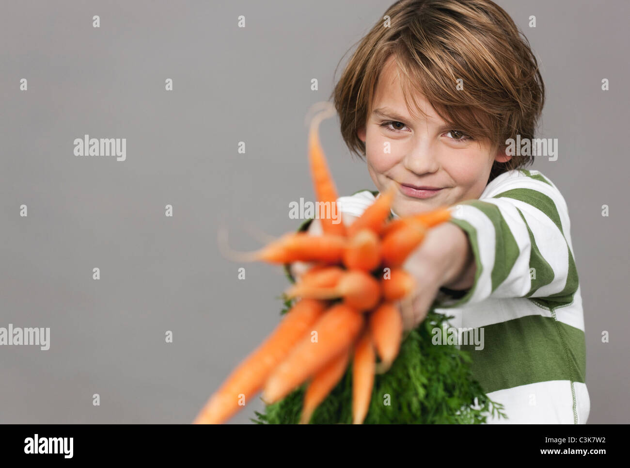 Boy holding a bunch of carrots, portrait Stock Photo - Alamy