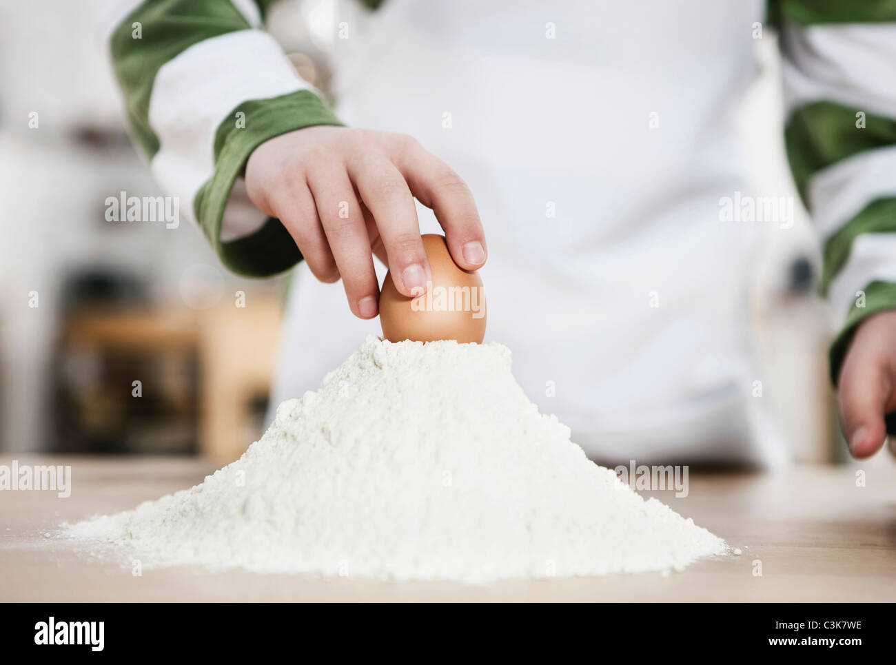 Germany, Cologne, Boy putting egg on heap of flour Stock Photo - Alamy