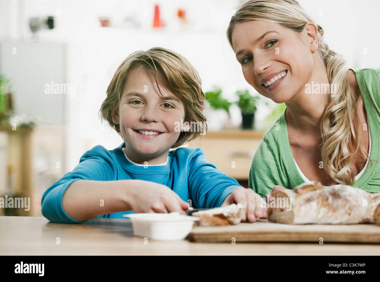 Germany, Cologne, Mother and son cutting bread in kitchen Stock Photo ...