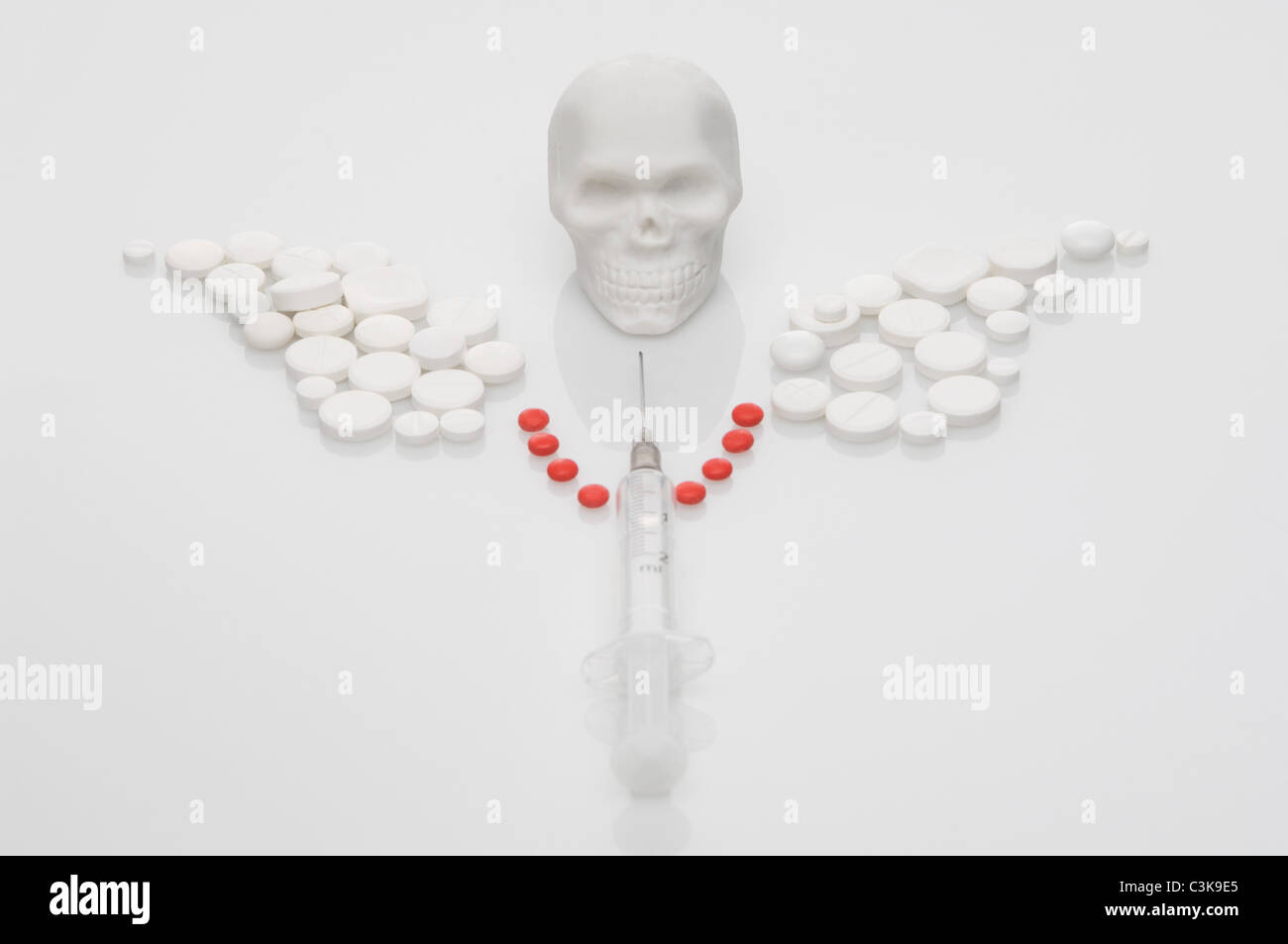 Skull, pills, drugs and syringe forming medical symbol on white ...