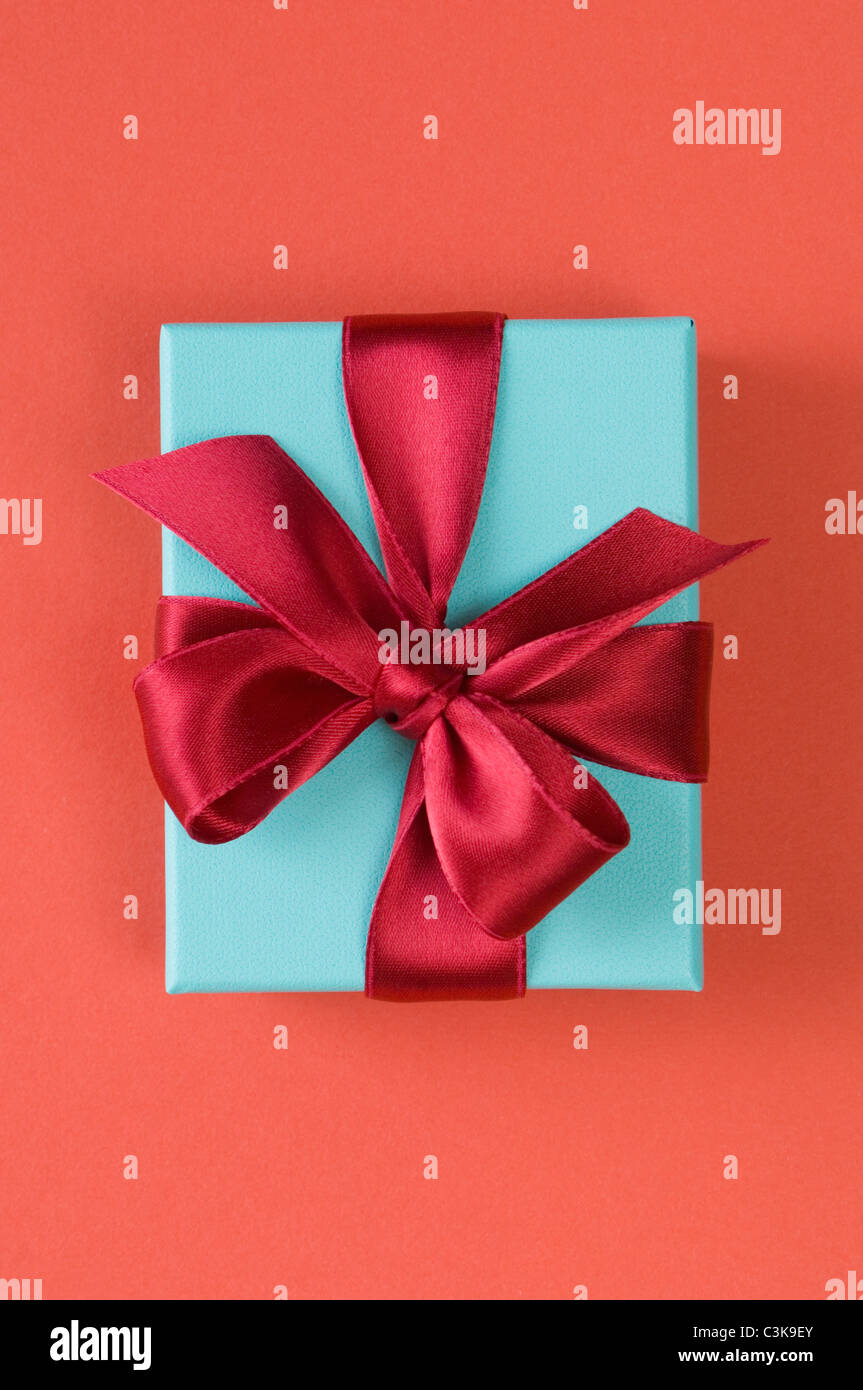 Gift box tied with red ribbon on red background Stock Photo - Alamy