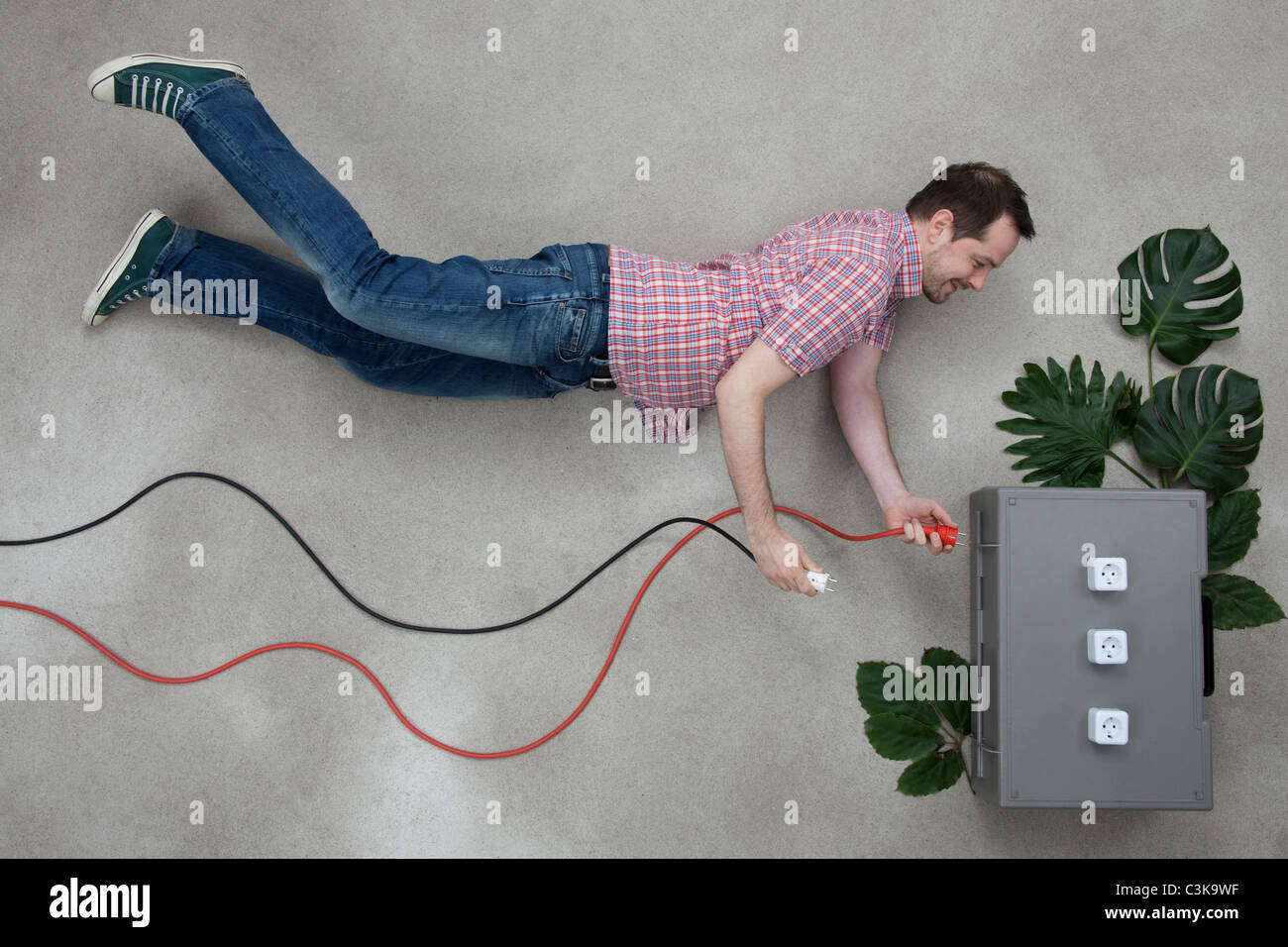 Mid adult man holding plug near electric socket Stock Photo - Alamy